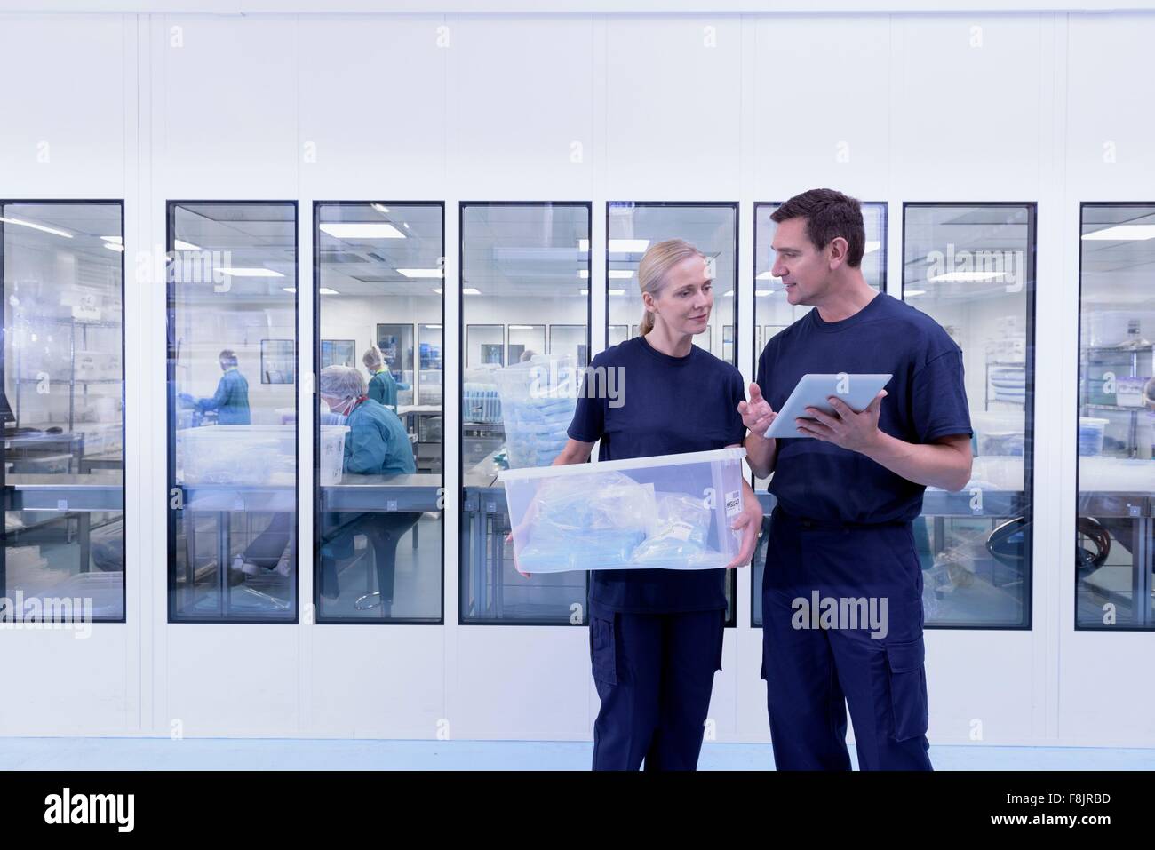 Workers with digital tablet inspecting products outside clean room in ...