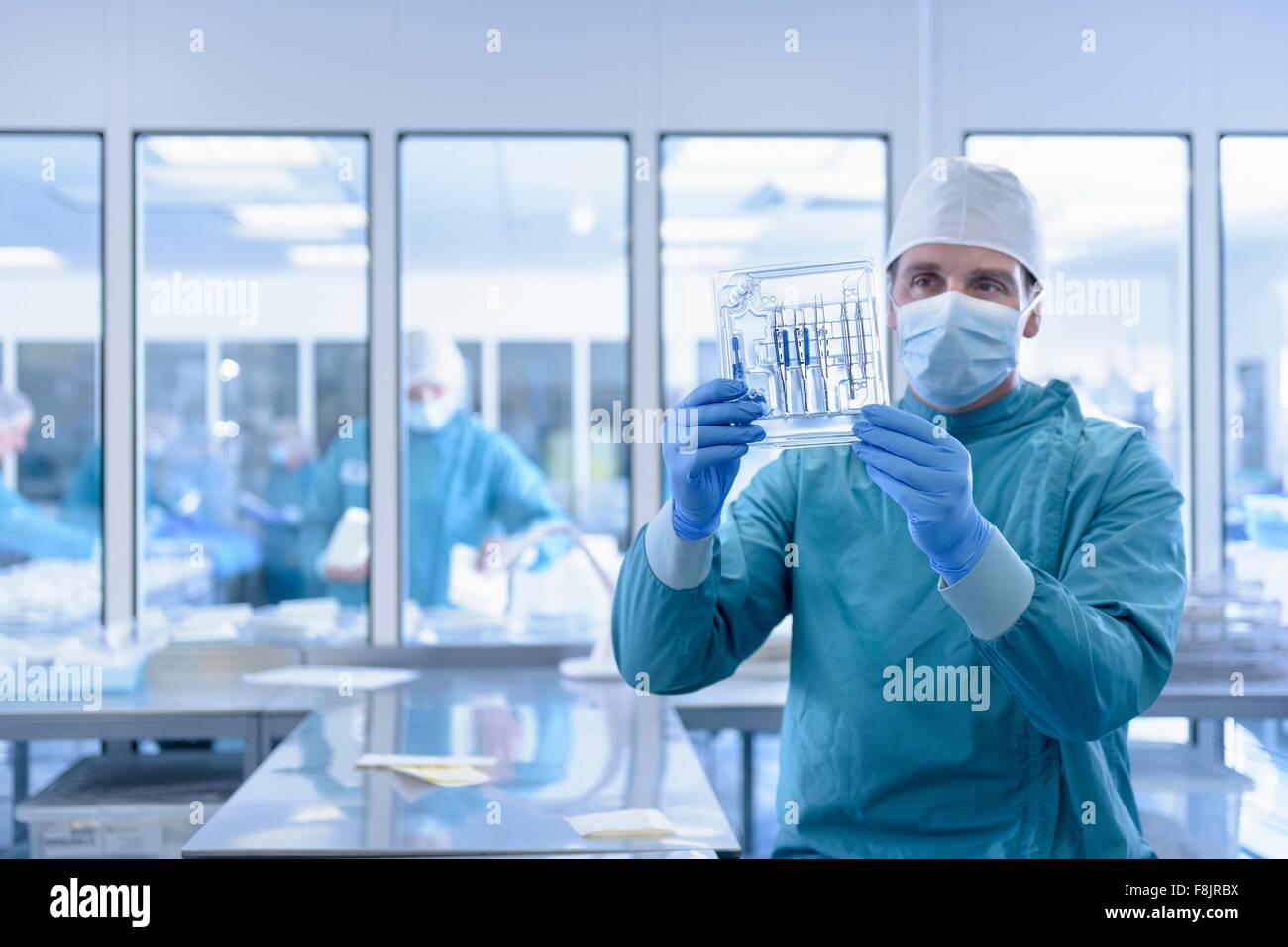 Worker inspecting surgical instruments in clean room of surgical ...