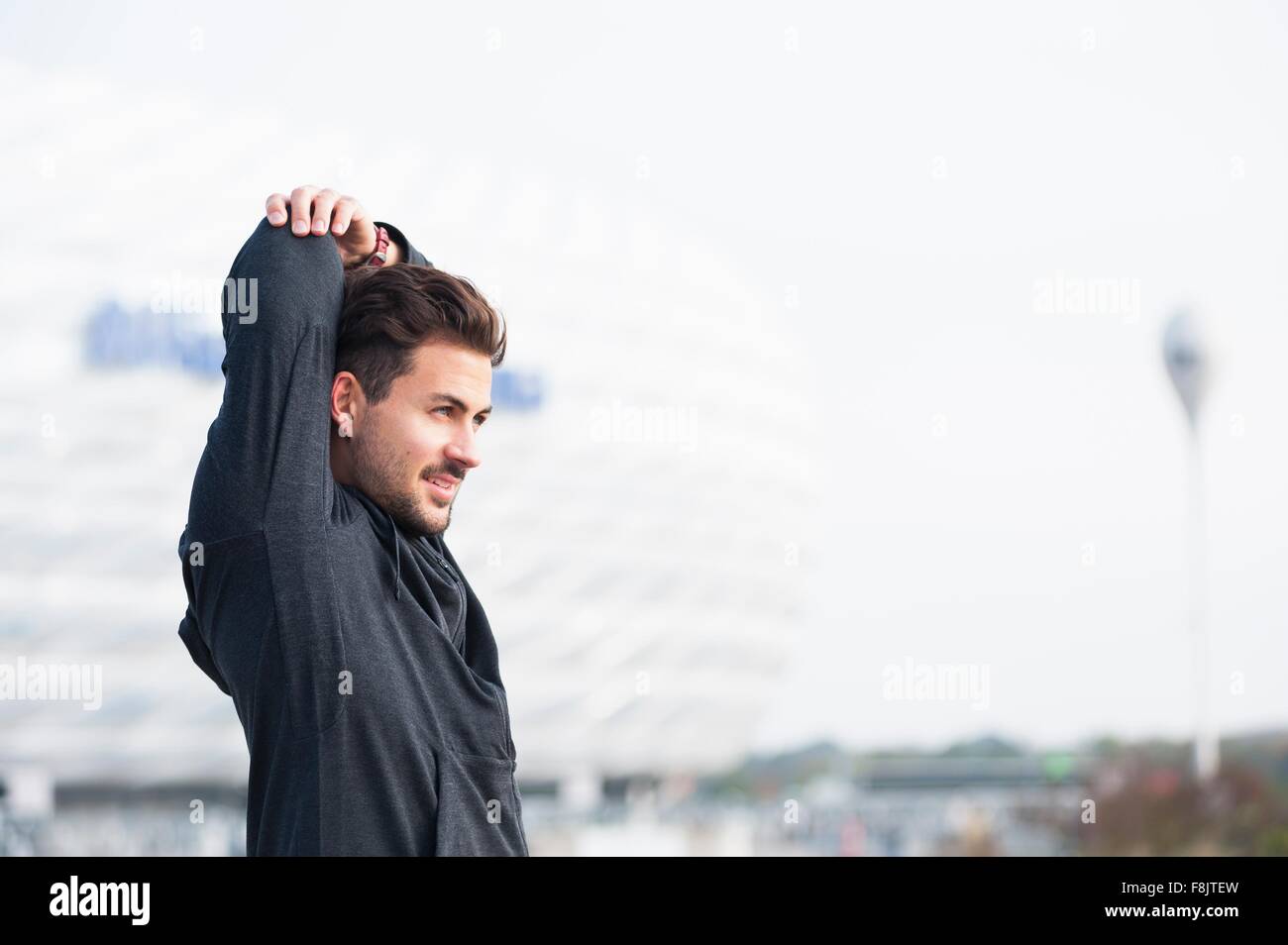 Young male runner stretching arms in sport arena Stock Photo - Alamy