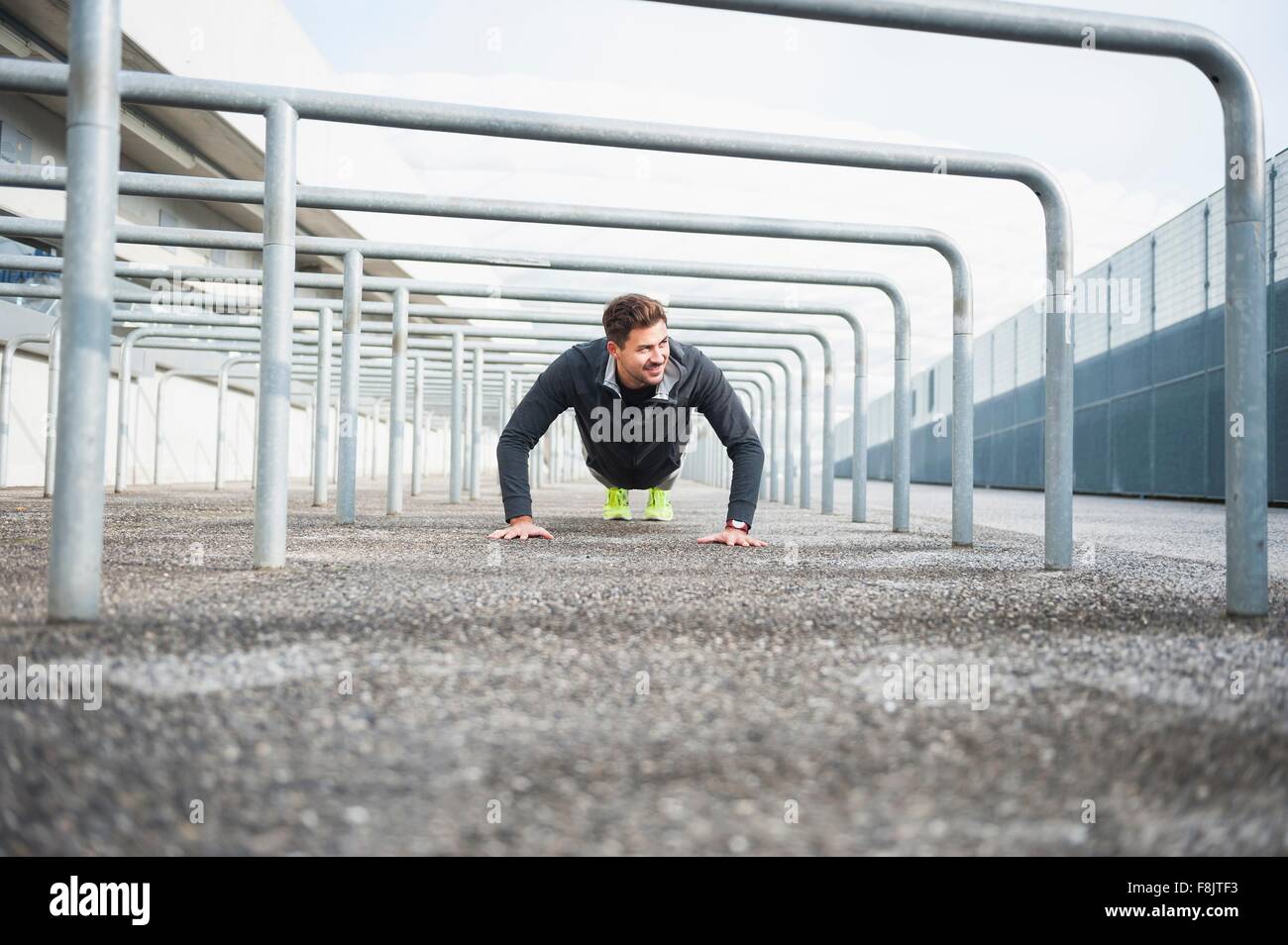 Surface level view of young male runner doing push ups in sport arena ...