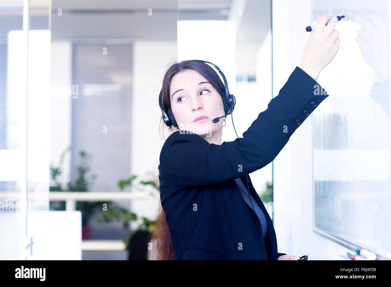 Telephonist writing on whiteboard in office Stock Photo - Alamy