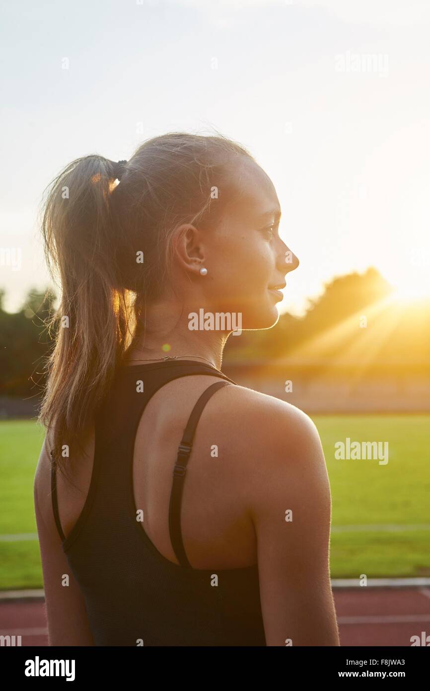 Portrait of young female runner on sunlit race track Stock Photo - Alamy