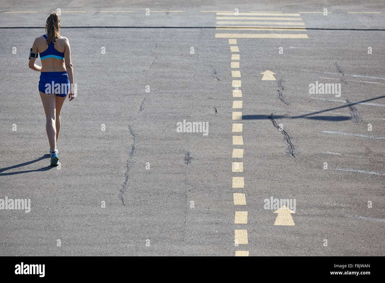 Rear view of young female runner running in parking lot Stock Photo - Alamy