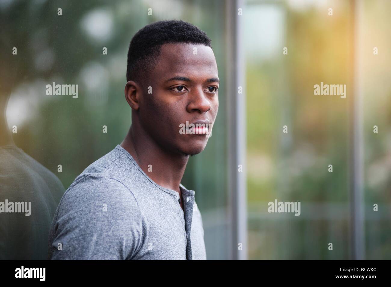 Portrait of young man, leaning against window, outdoors Stock Photo - Alamy
