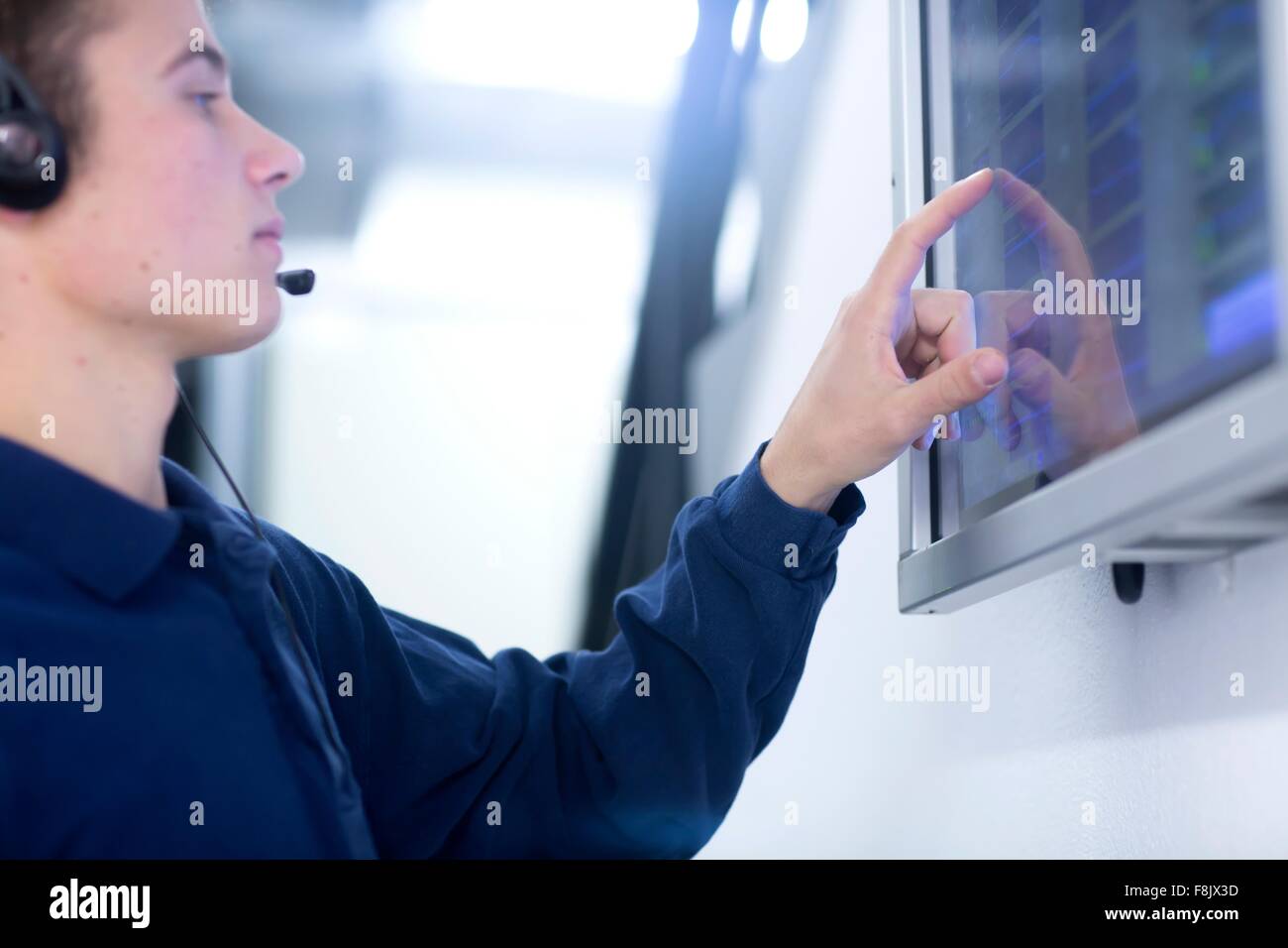 Low angle side view of young man wearing headset using touch screen ...