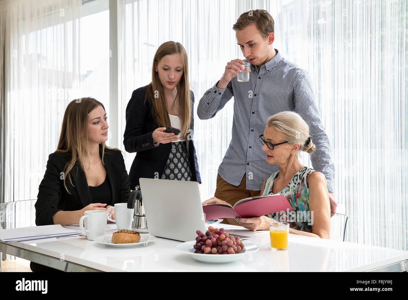 Colleagues at table having breakfast meeting looking at paperwork Stock ...