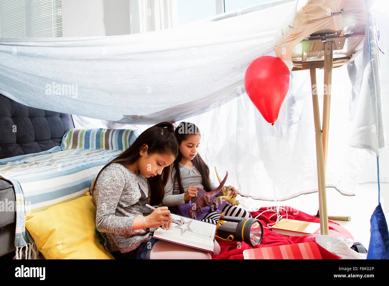 Two young girls, sitting inside home-made tent, playing Stock Photo - Alamy