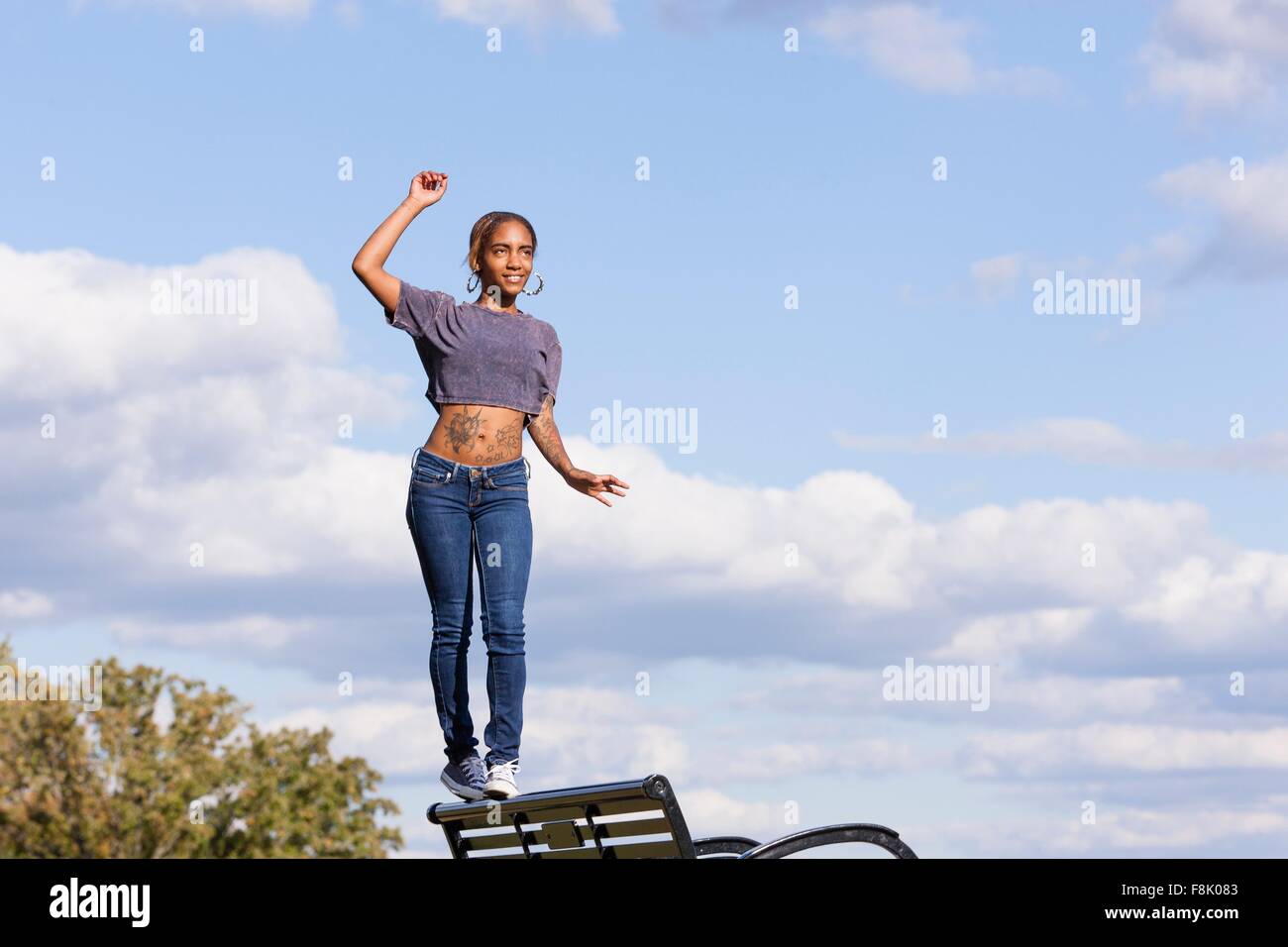 Young woman wearing crop top balancing on back on park bench Stock ...