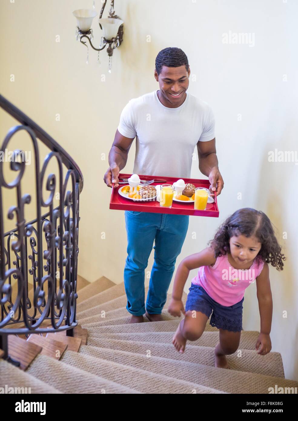 Father and daughter walking up stairs carrying breakfast on tray Stock ...
