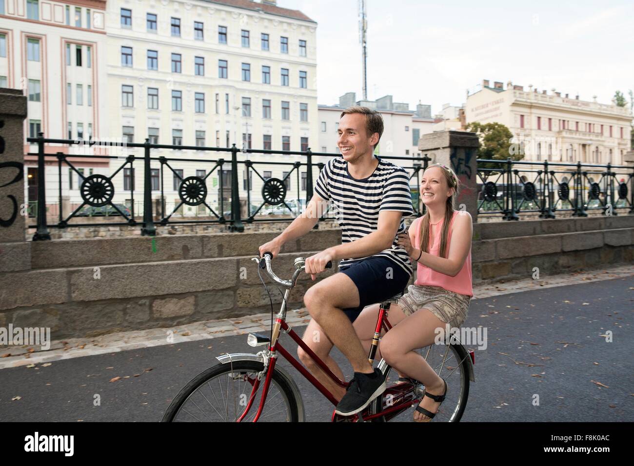Young man riding bicycle with young woman sitting on back smiling Stock ...