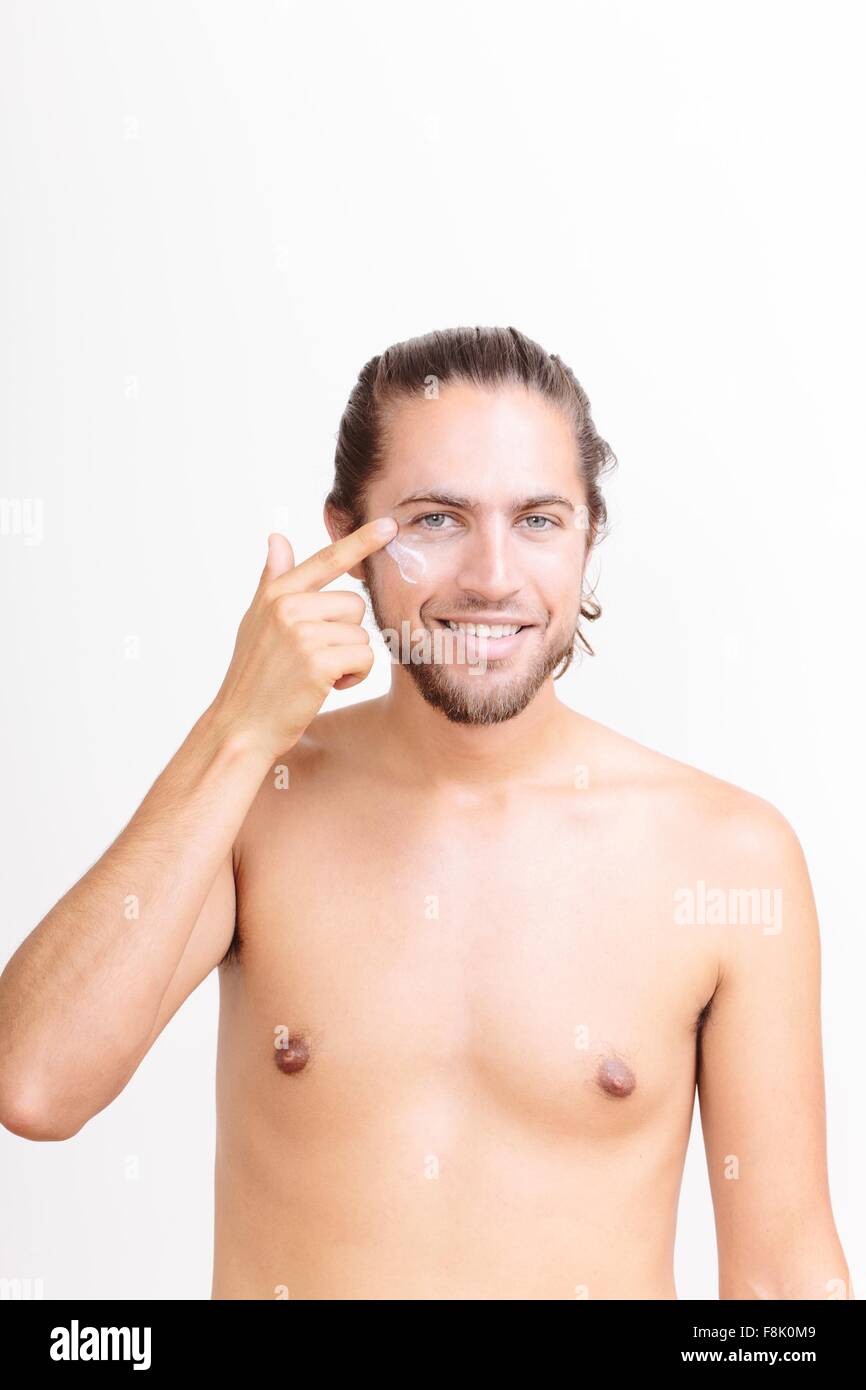 Portrait of young man applying moisturiser Stock Photo - Alamy