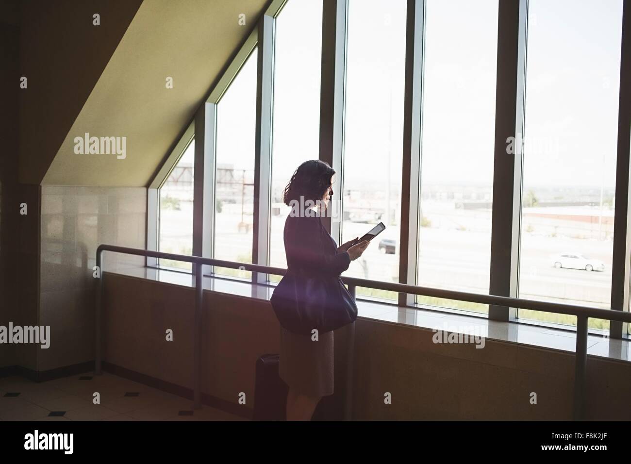 Mid adult woman standing beside window, holding digital tablet Stock ...