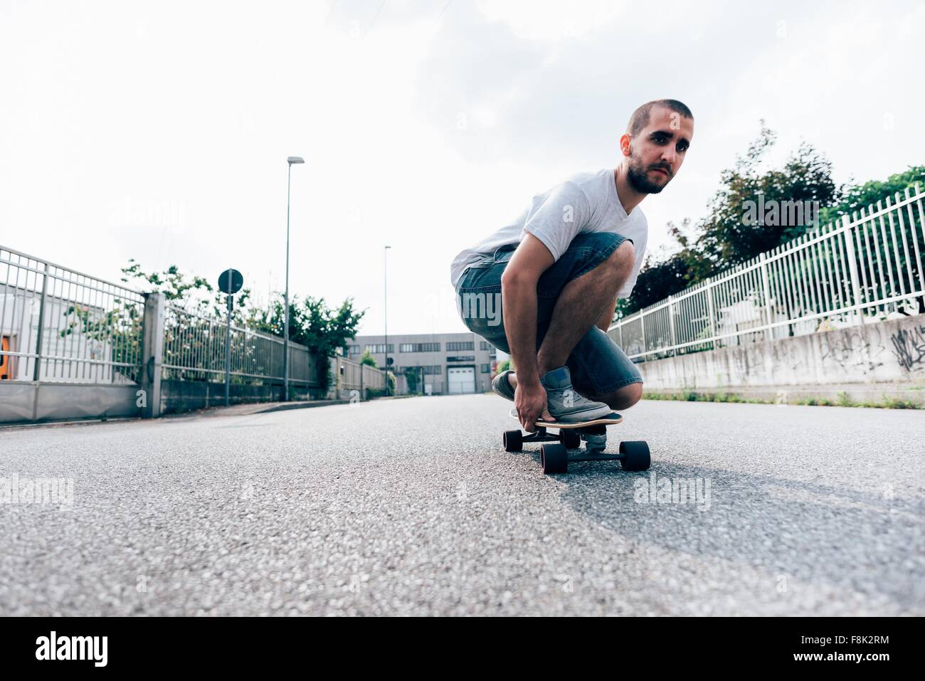 Young man crouched on skateboard Stock Photo - Alamy