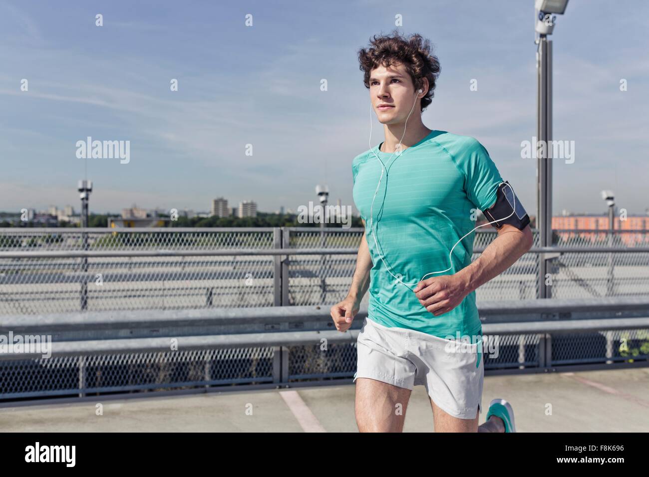 Young male runner wearing earphones whilst running in city Stock Photo ...