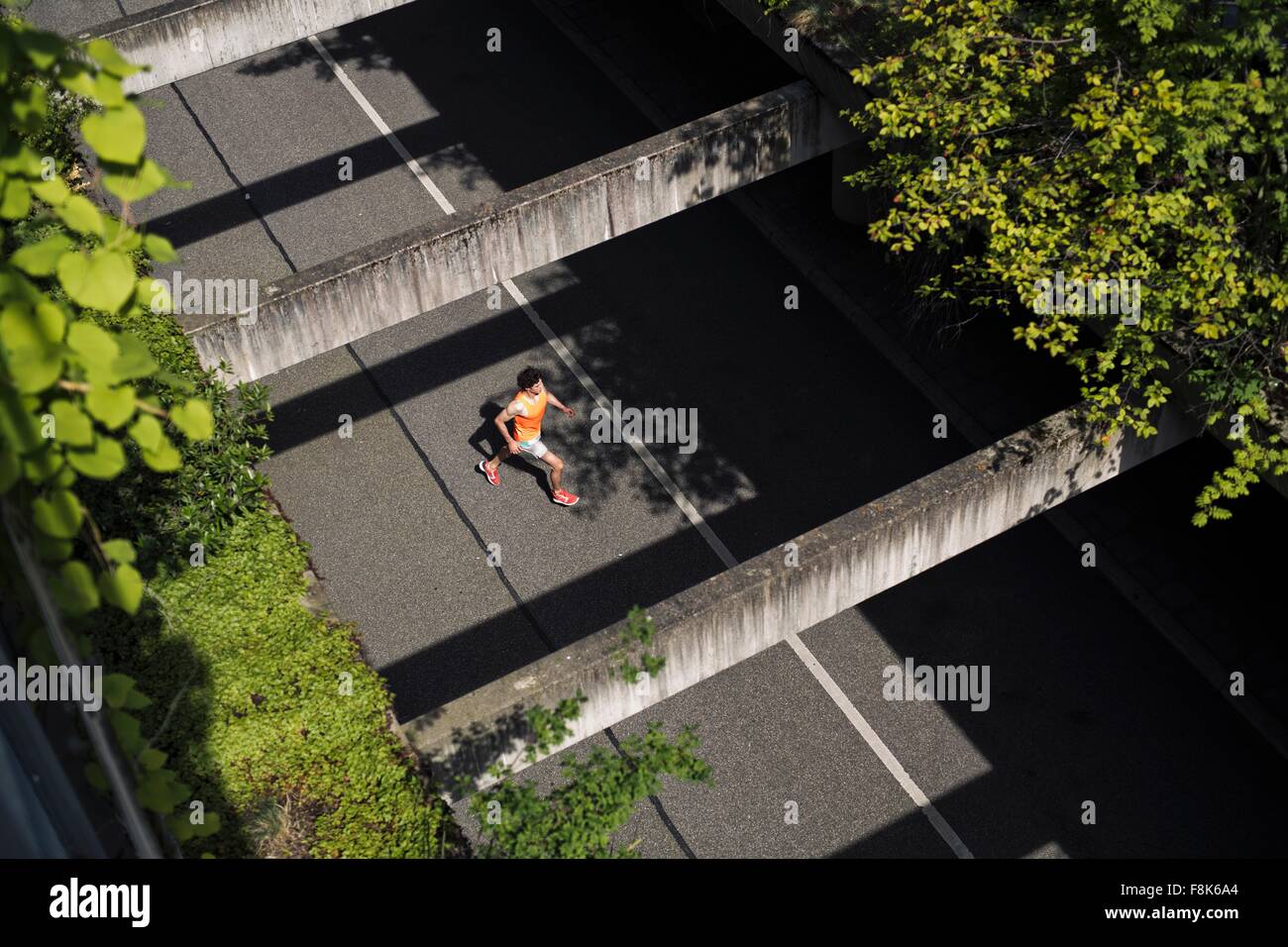 Overhead view of young male runner running along city underpass Stock ...