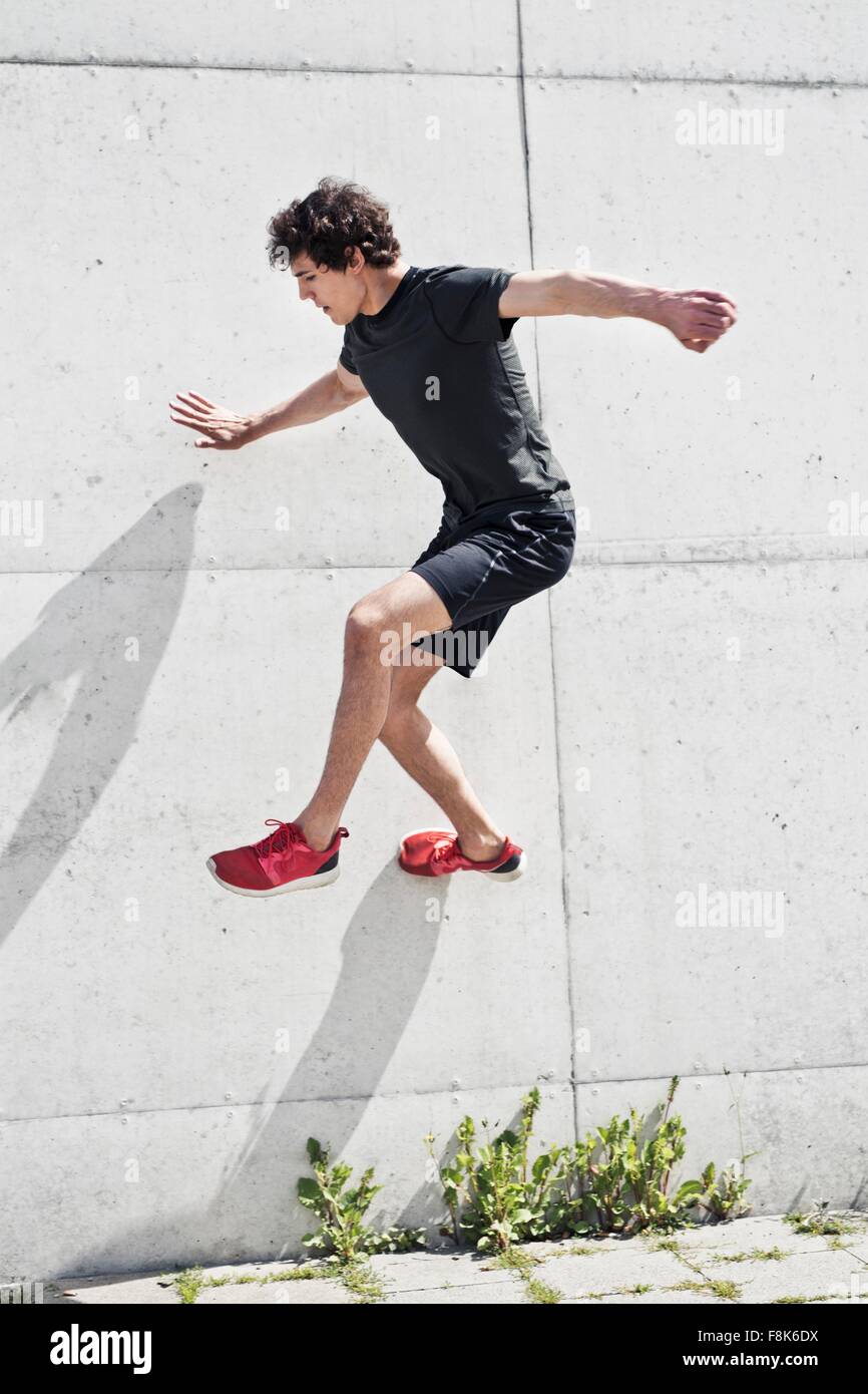 Young man free running against concrete wall Stock Photo - Alamy