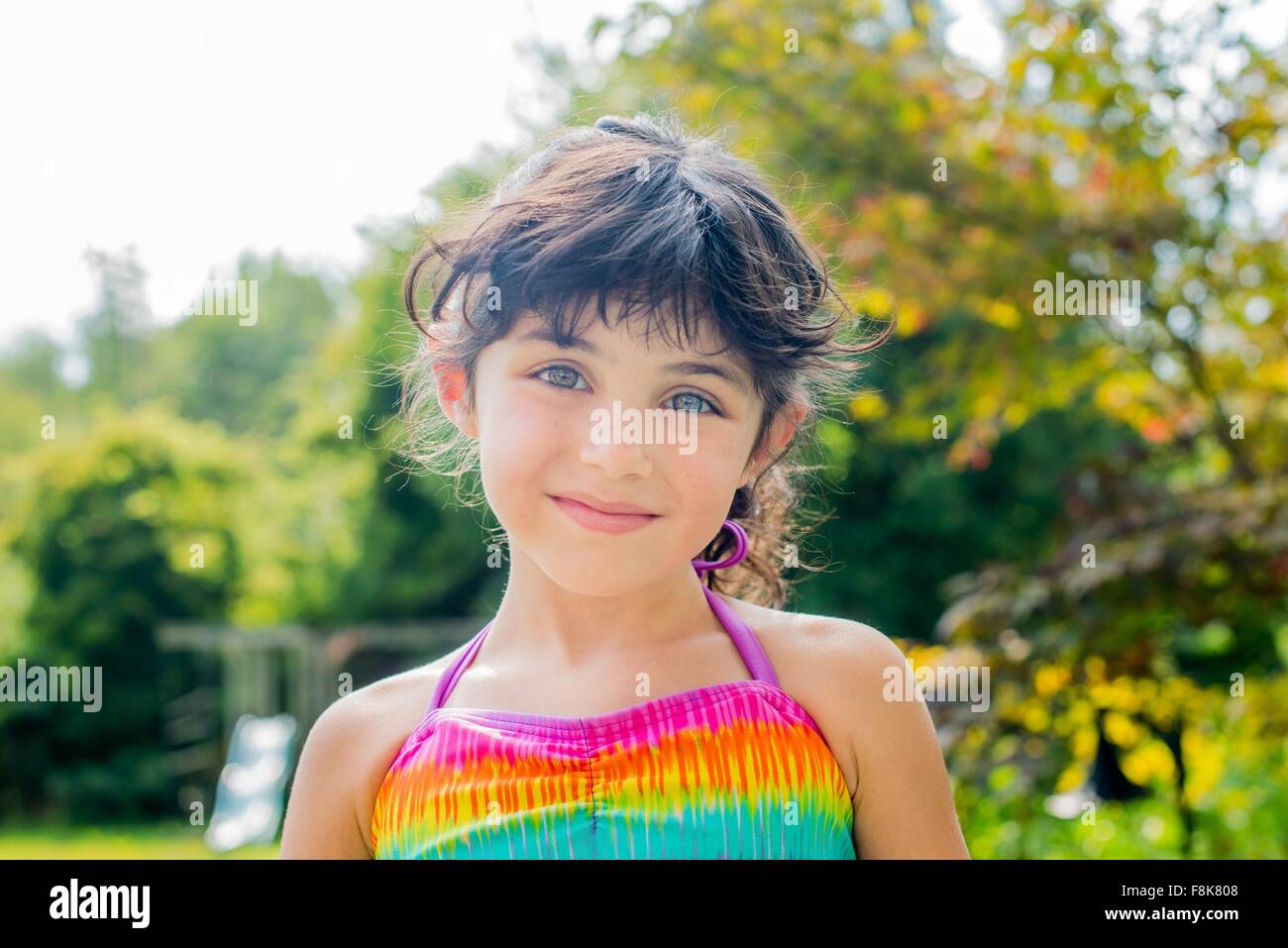 Portrait of girl wearing colourful halter top looking at camera smiling ...