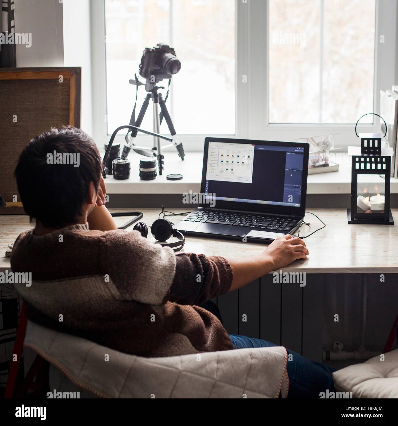 Mid adult man sitting at desk using laptop, rear view Stock Photo - Alamy