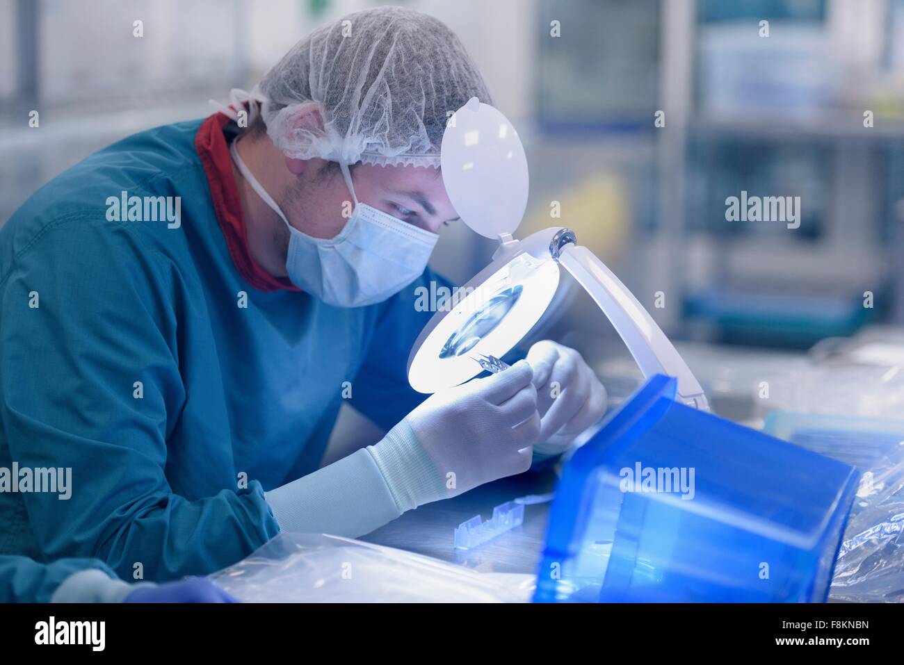 Worker inspecting surgical instruments in clean room of surgical ...