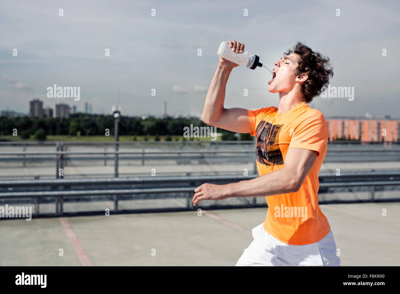 Young male runner drinking water whilst city running Stock Photo - Alamy