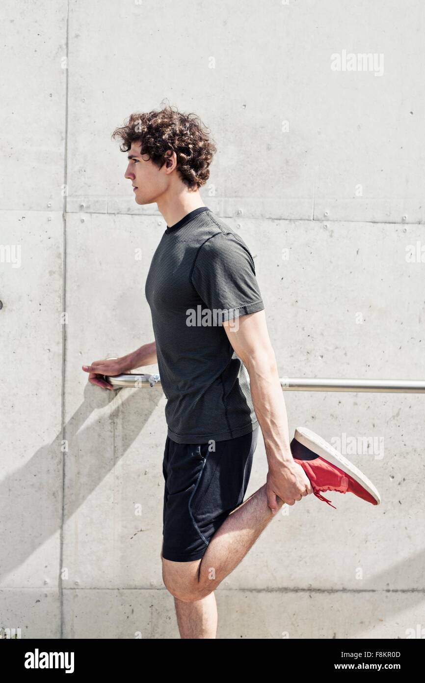 Young male runner stretching legs in city Stock Photo - Alamy