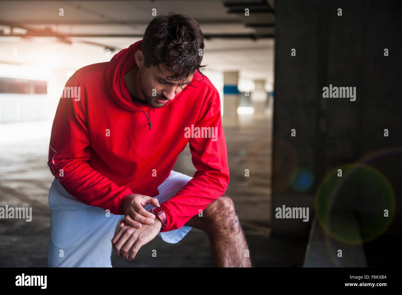 Young male runner checking smartwatch in parking lot Stock Photo - Alamy