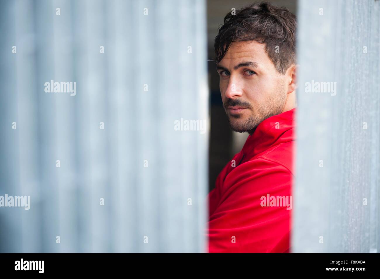 Portrait of suspicious young man looking over his shoulder between ...