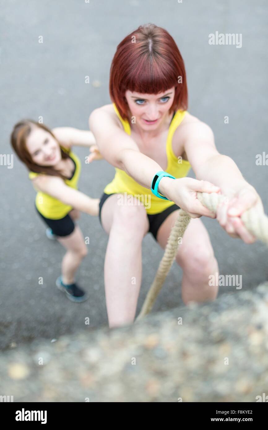 Young women climbing over wall with rope Stock Photo - Alamy
