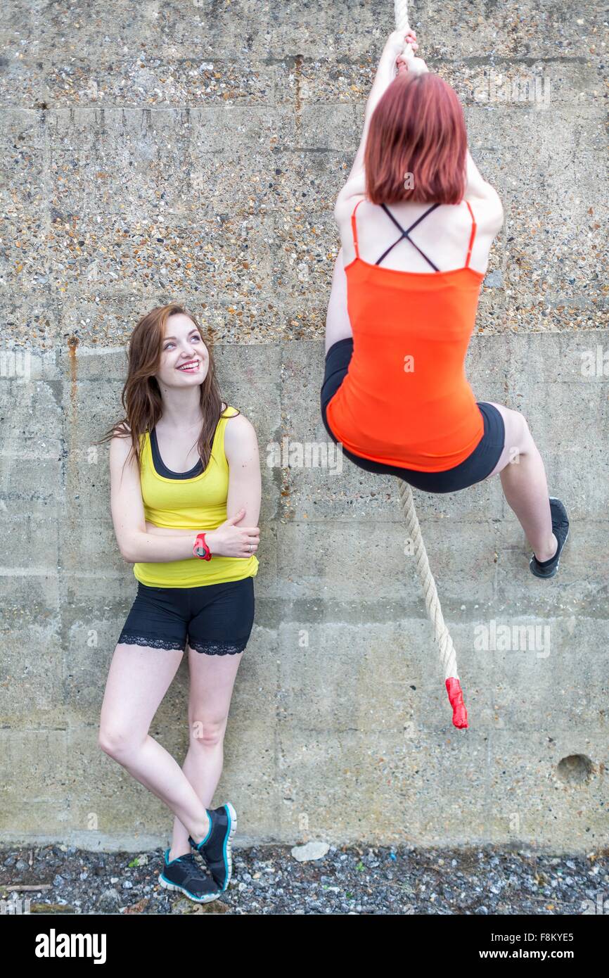 Young women climbing over wall with rope Stock Photo - Alamy