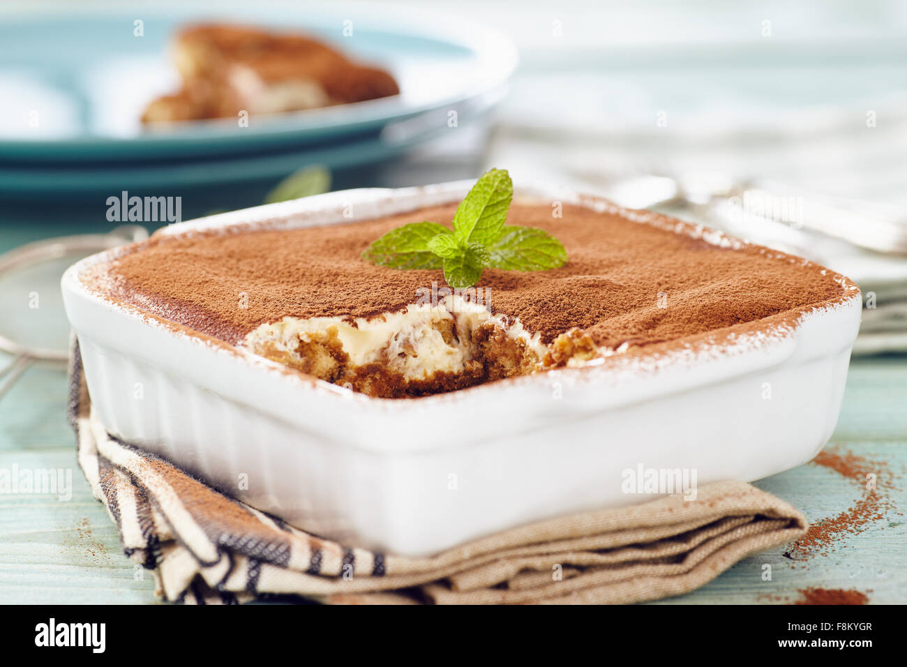 Tiramisu cake in an oven pan on a blue wooden table with dishes and ...