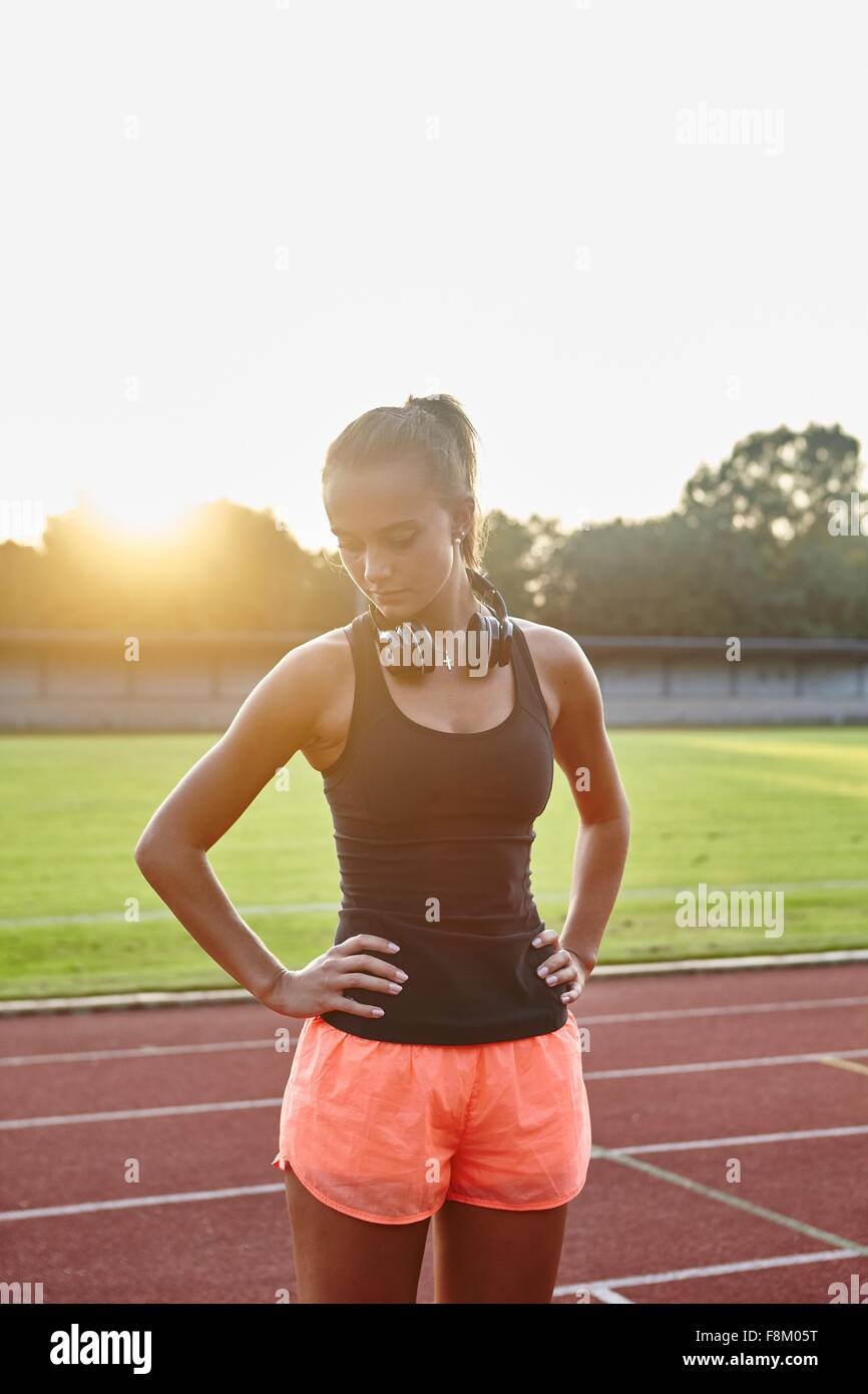 Young female runner on race track with hands on hips Stock Photo - Alamy