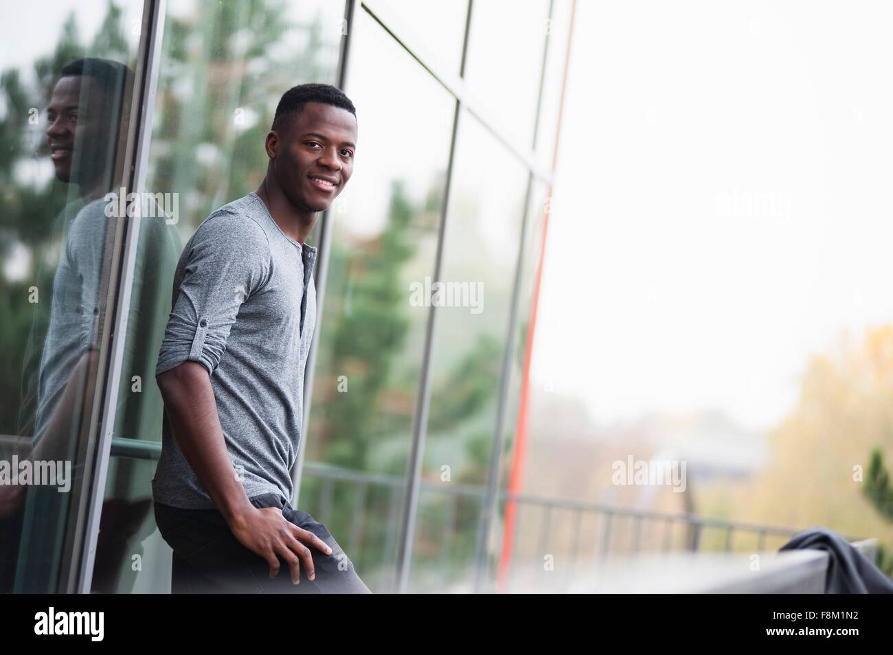 Portrait of young man, leaning against window, smiling, outdoors Stock ...