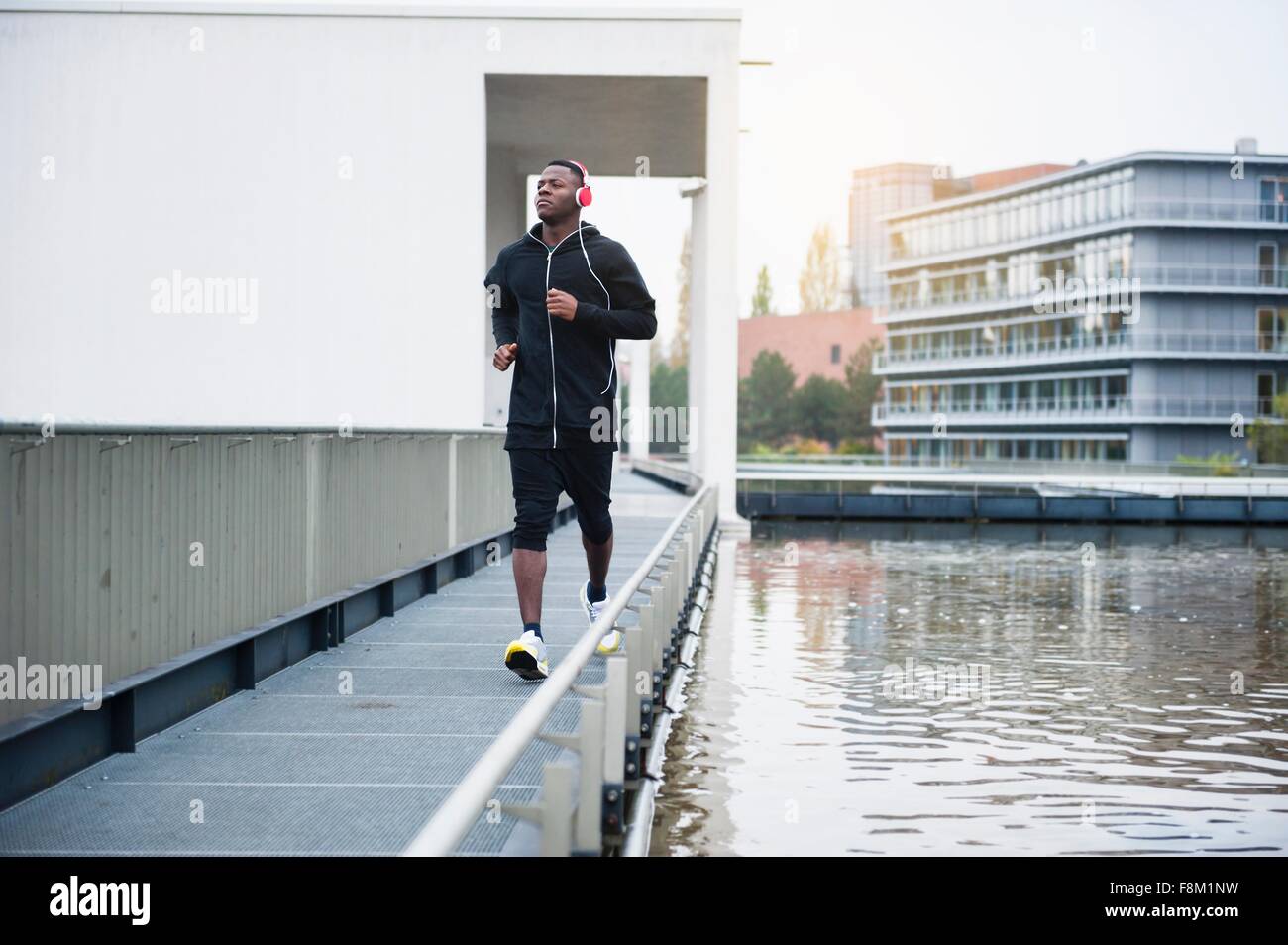 Young man running beside river Stock Photo - Alamy