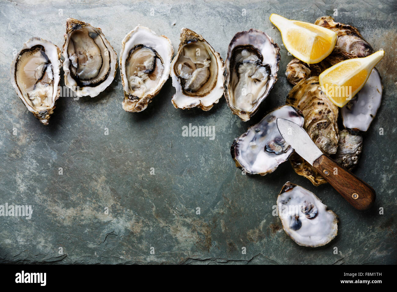 Open Oysters Fines de Claire on stone plate background with lemon and ...