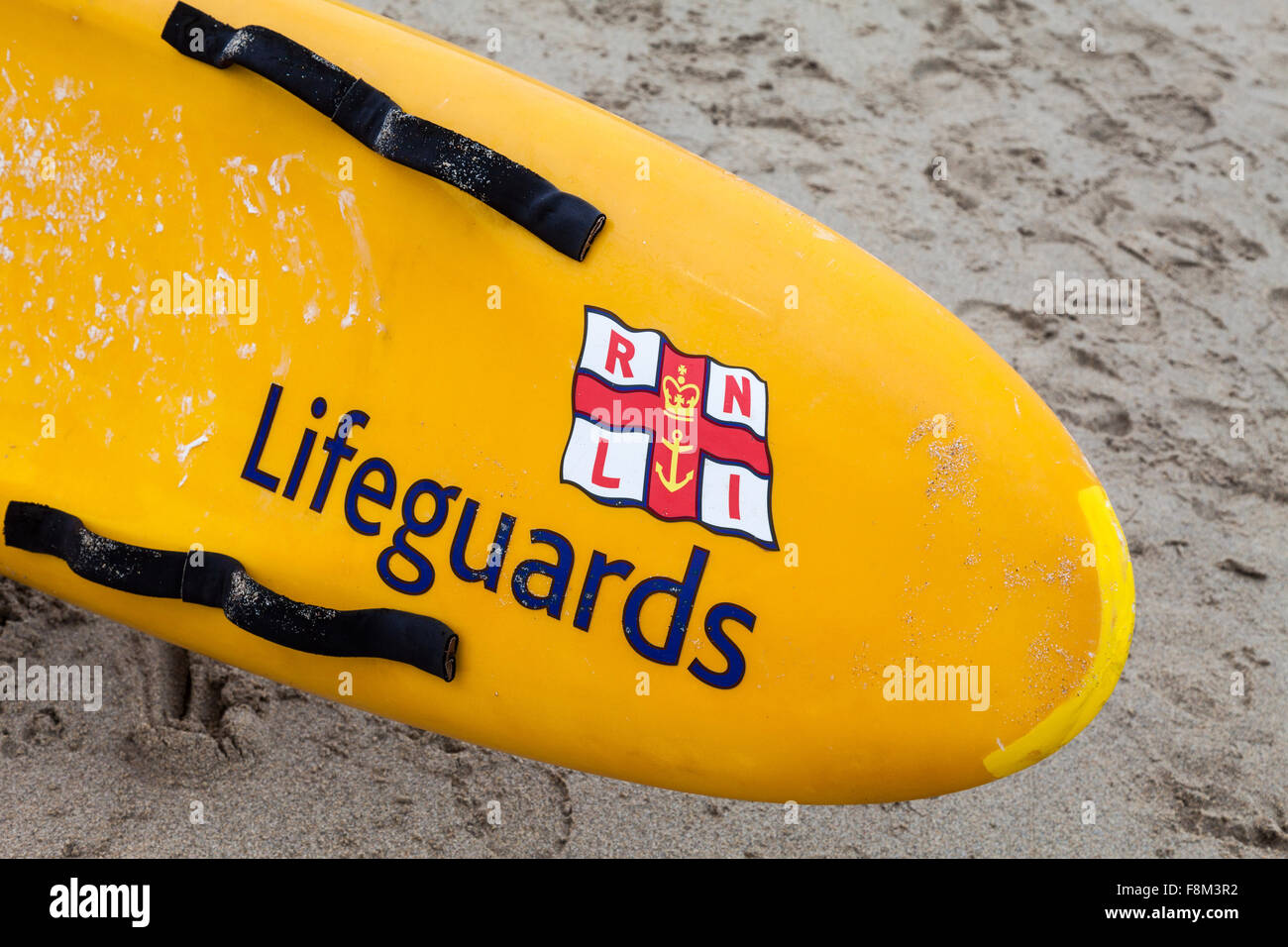 A Royal National Lifeboat Institution RNLI lifeguards rescue surf board ...