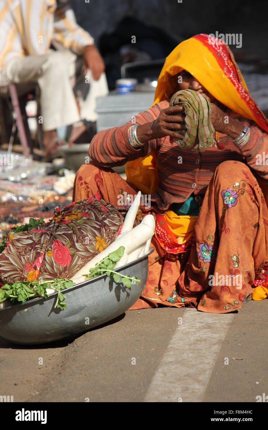 PUSHKAR, INDIA - NOV 29: Old Indian woman selling vegetables in the street of Pushkar with a ...