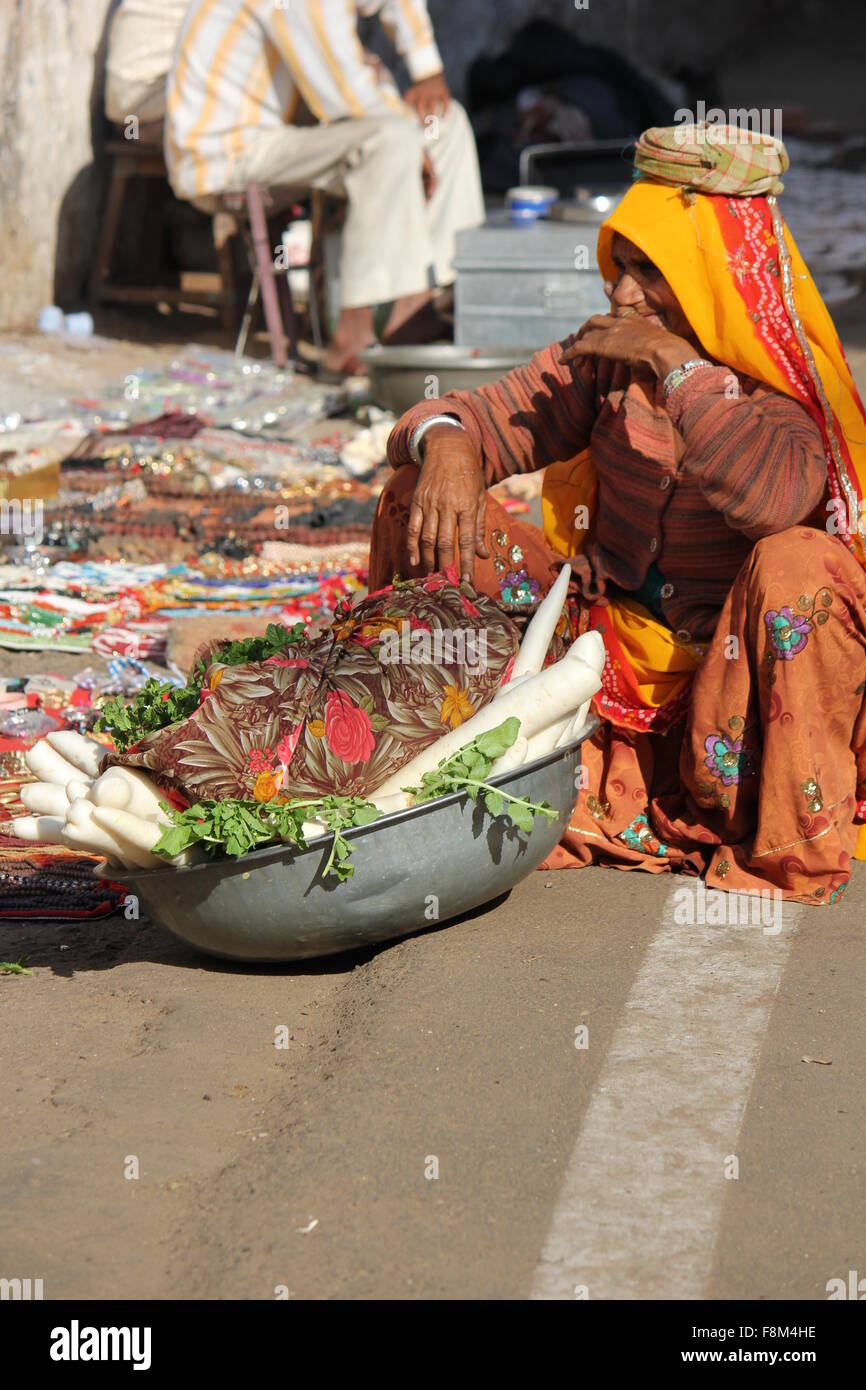 PUSHKAR, INDIA - NOV 29: Old Indian woman selling vegetables in the street of Pushkar with a ...