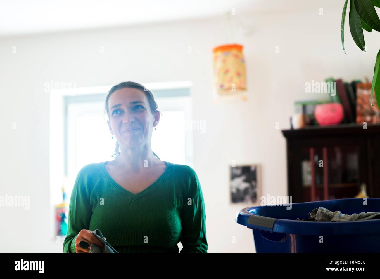 Mid adult woman sorting clothing in laundry basket, looking away ...