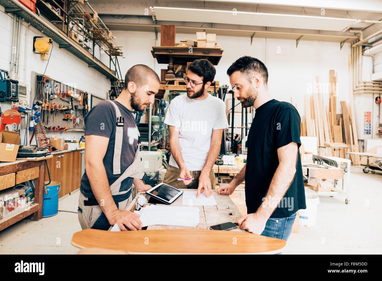 Friends standing around workbench in carpentry workshop talking Stock ...