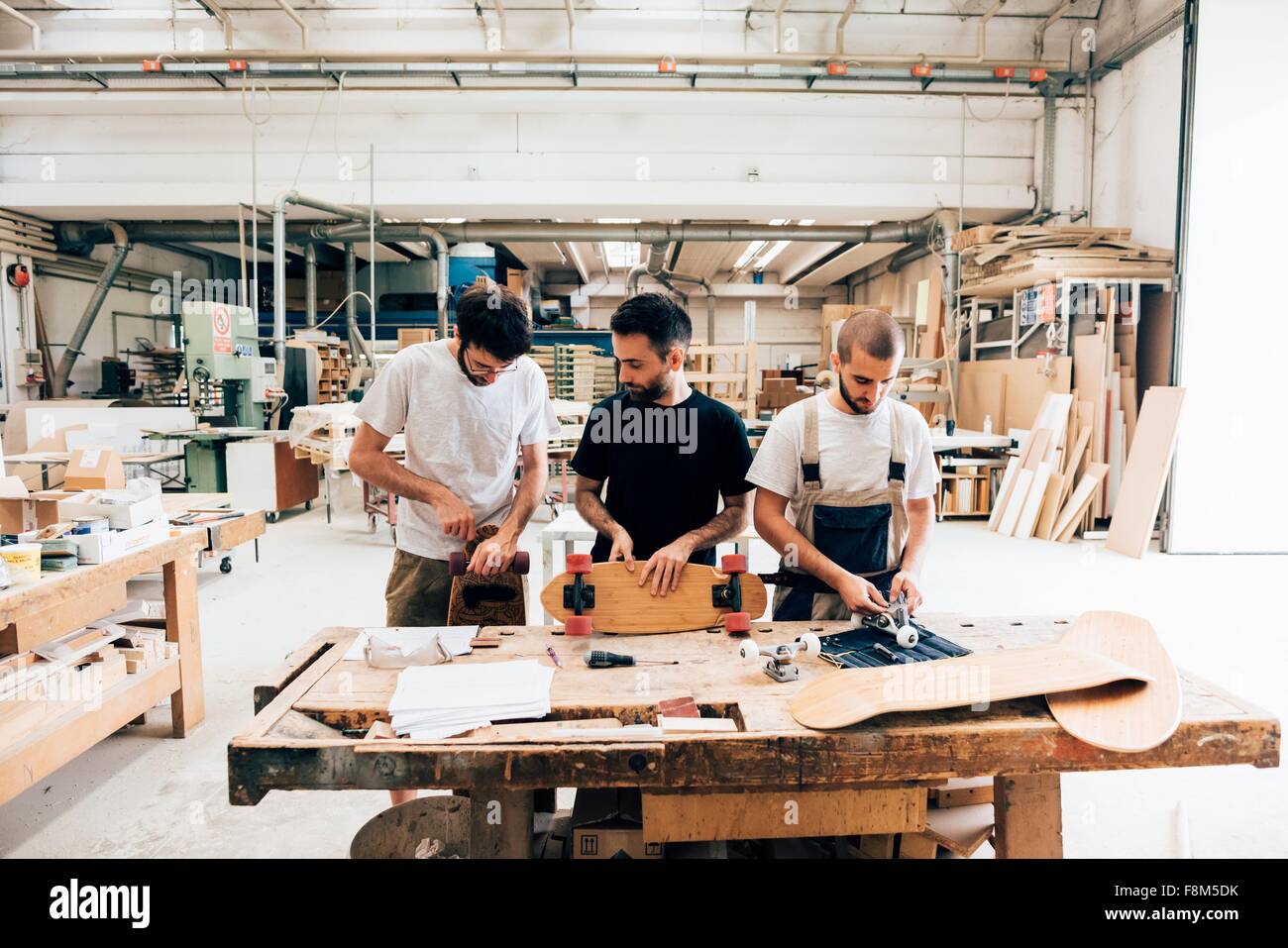 Front view of young men in carpentry workshop standing at workbench ...