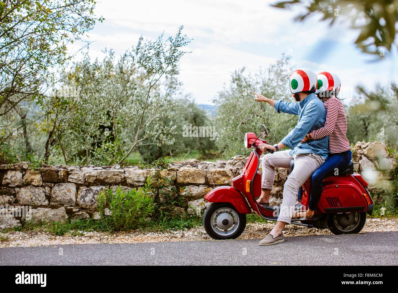 Young couple on moped pointing at olive grove, Florence, Italy Stock ...