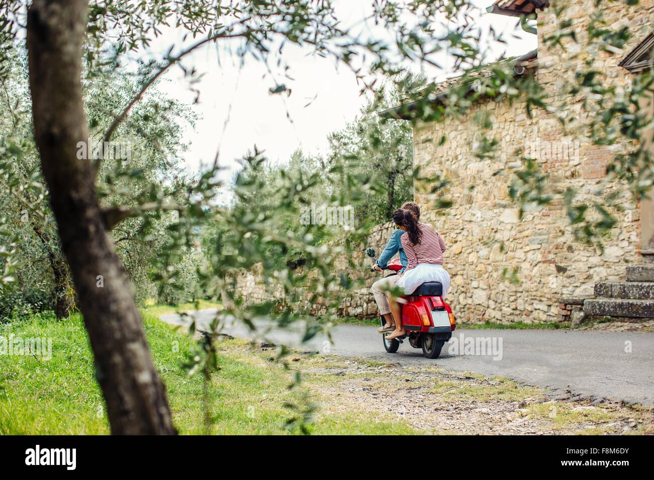 Rear view of young couple riding moped in village, Florence, Italy ...