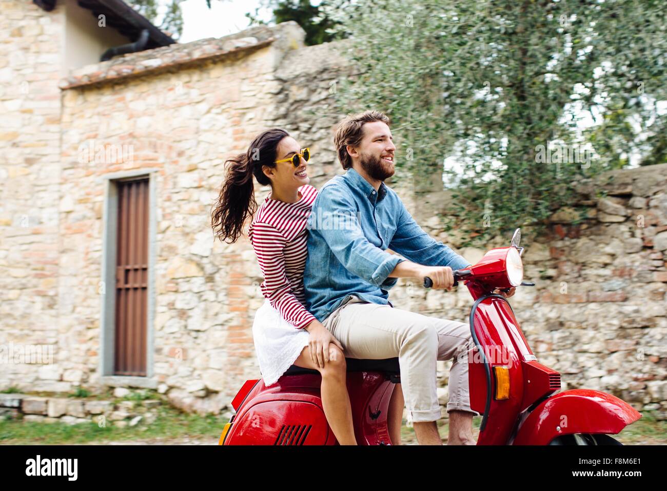 Side view of young couple riding moped in village, Florence, Italy Stock Photo - Alamy