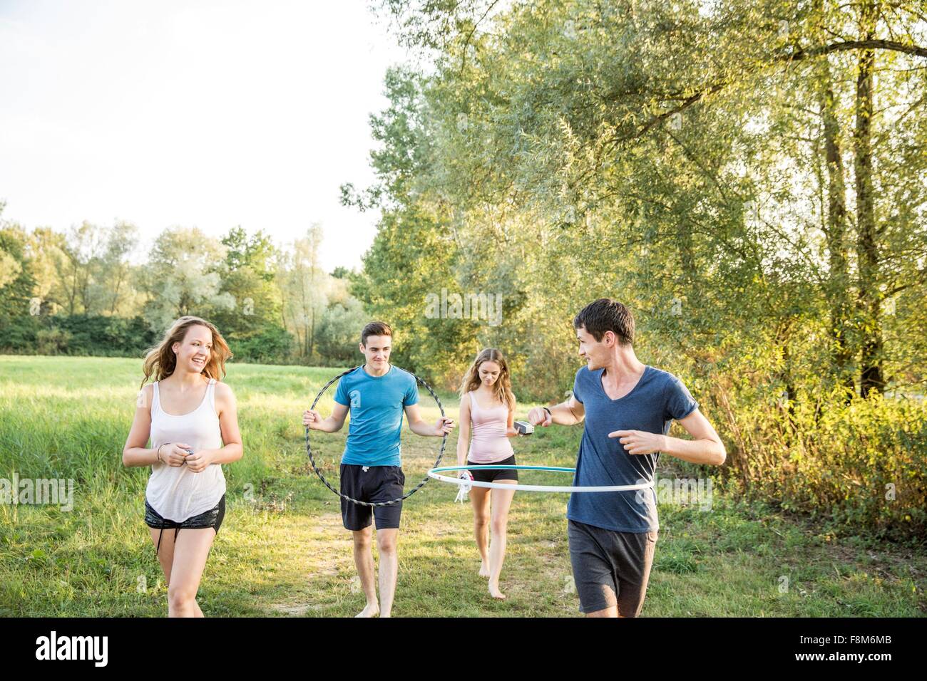 Group of friends in field, using hula hoops Stock Photo - Alamy