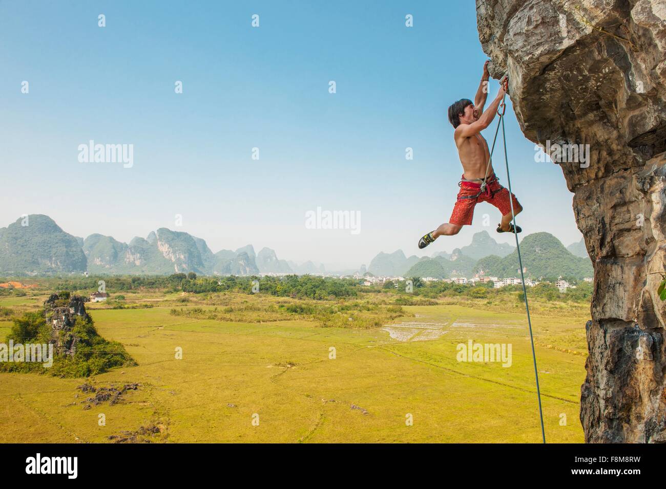 Male climber hanging from the Egg - a lime stone cliff in Yangshuo ...