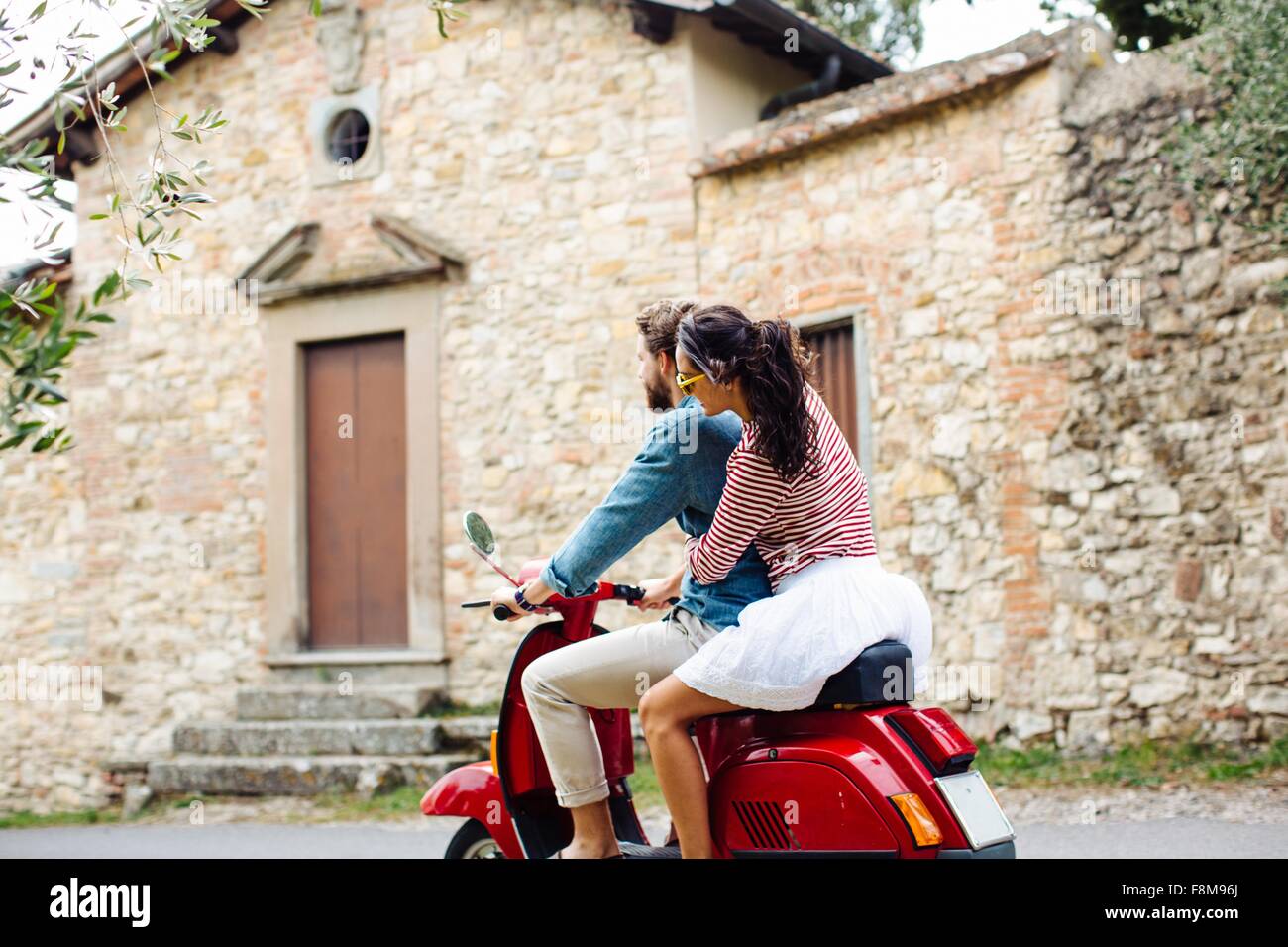 Young couple riding moped in village, Florence, Italy Stock Photo - Alamy