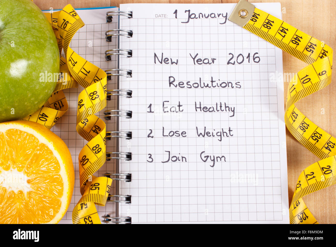 New years resolutions eat healthy, lose weight and join gym written in notebook and tape measure ...