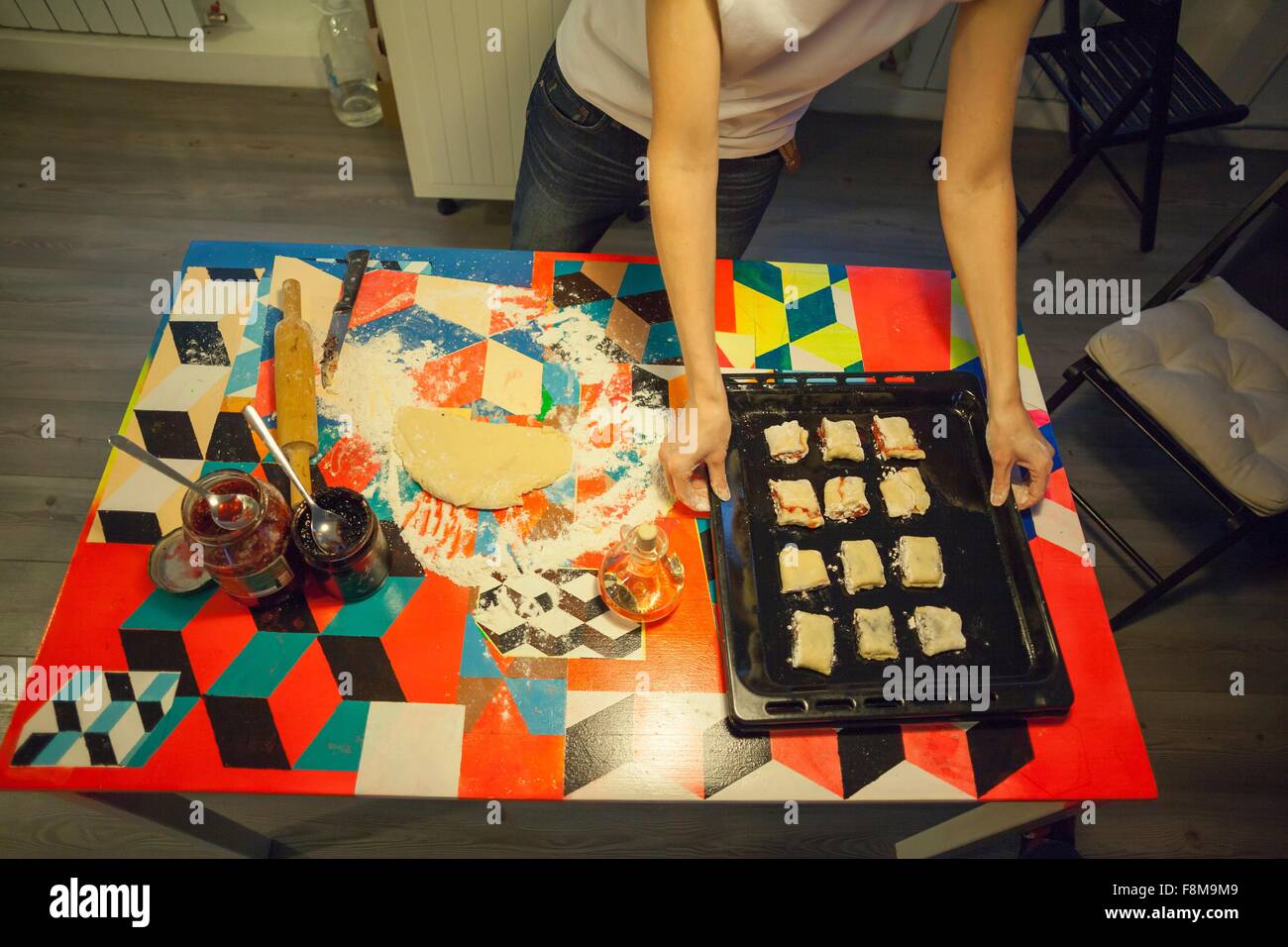 Overhead view of woman lifting baking tray from kitchen table Stock ...