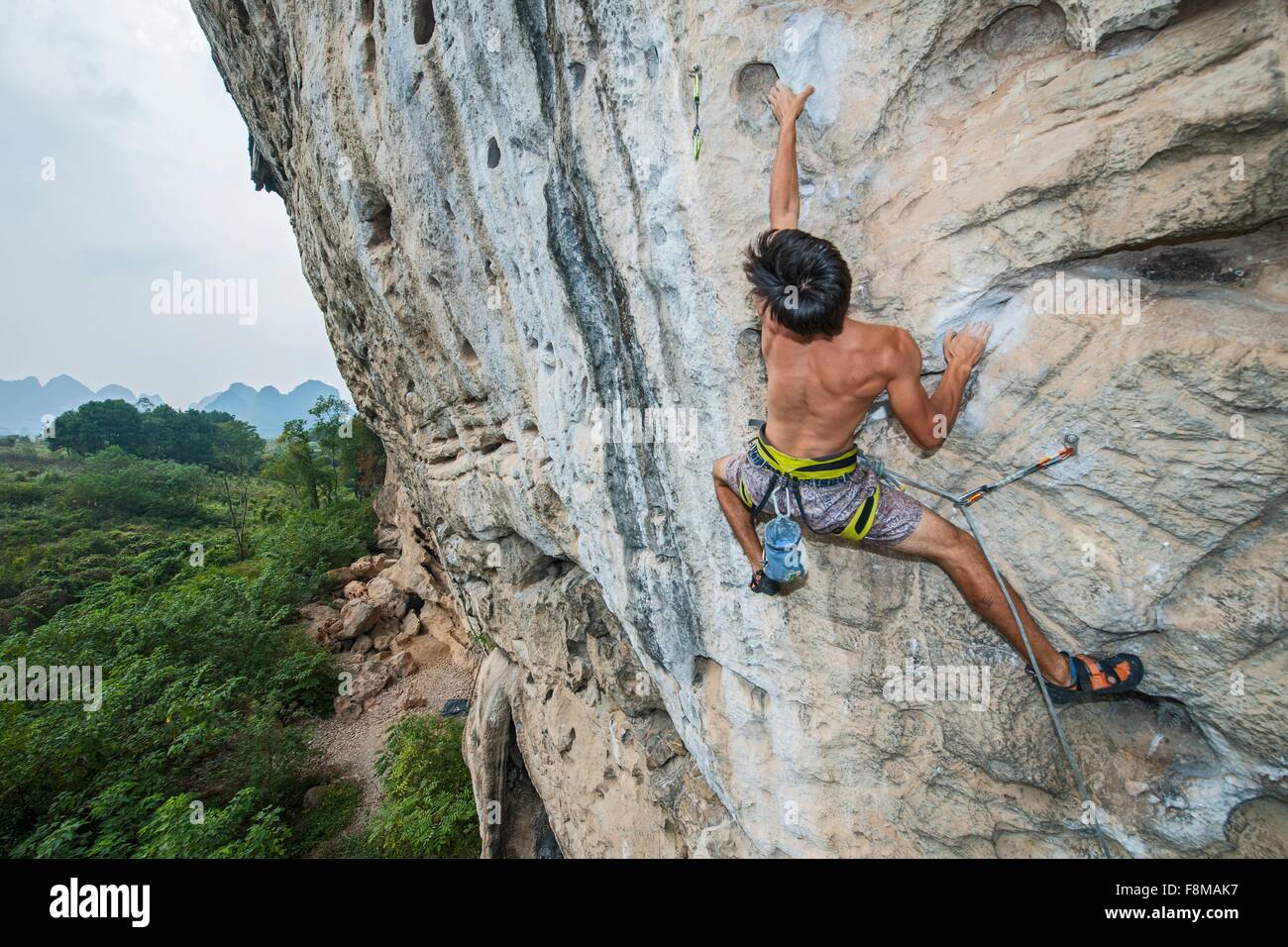 Male climber climbing at white Mountain - a limestone cliff in Yangshuo ...