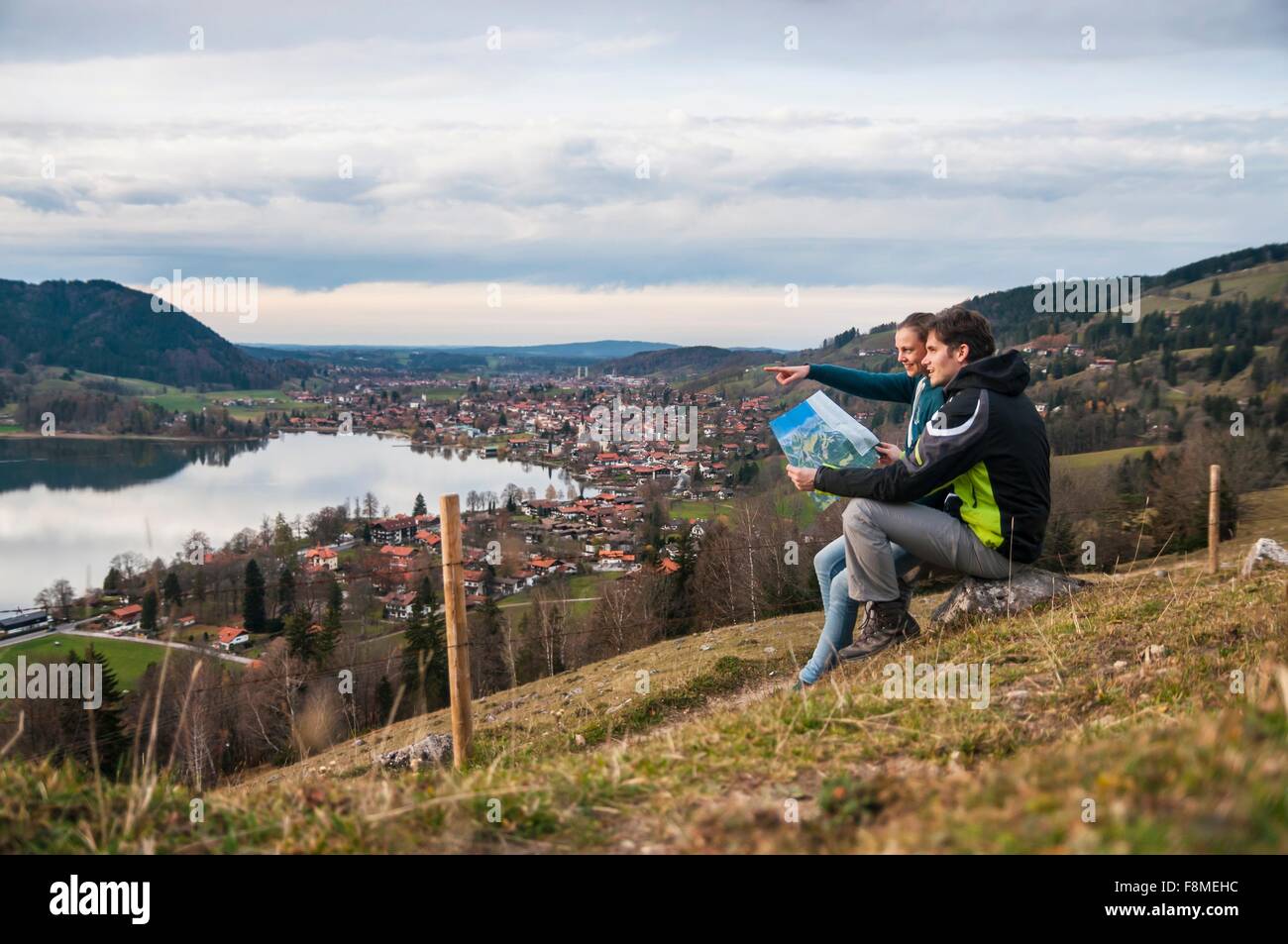 Side view of couple sitting looking at view of lake, holding map ...